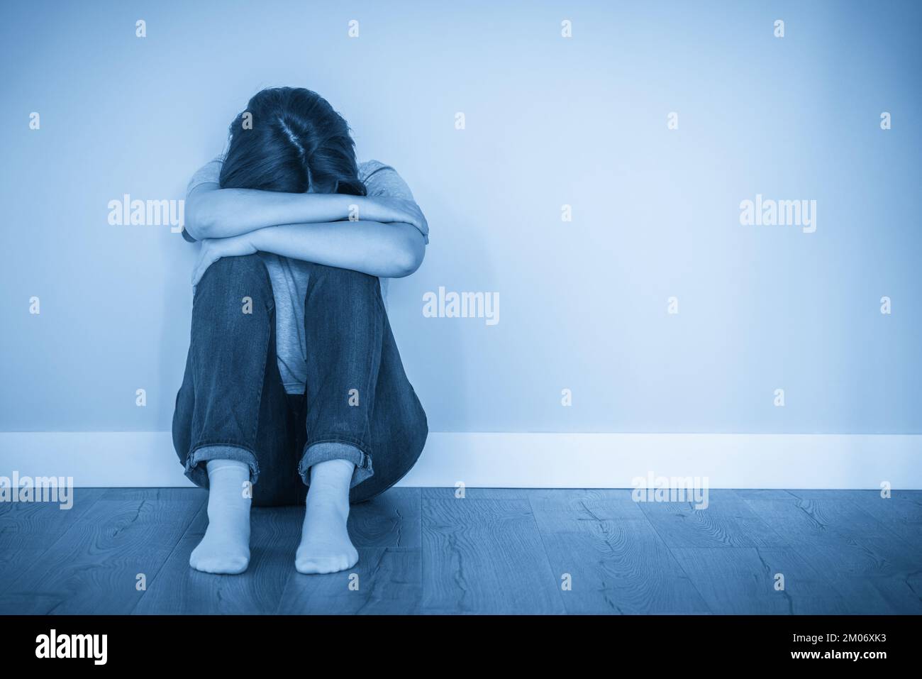 Sad woman sitting on a floor alone in empty room, despair and lonely ...