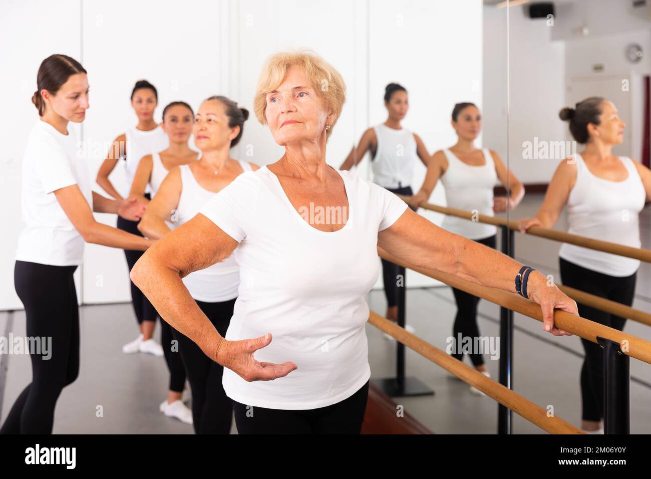 Group of ballerina standing with one hand on barre and reaching over ...