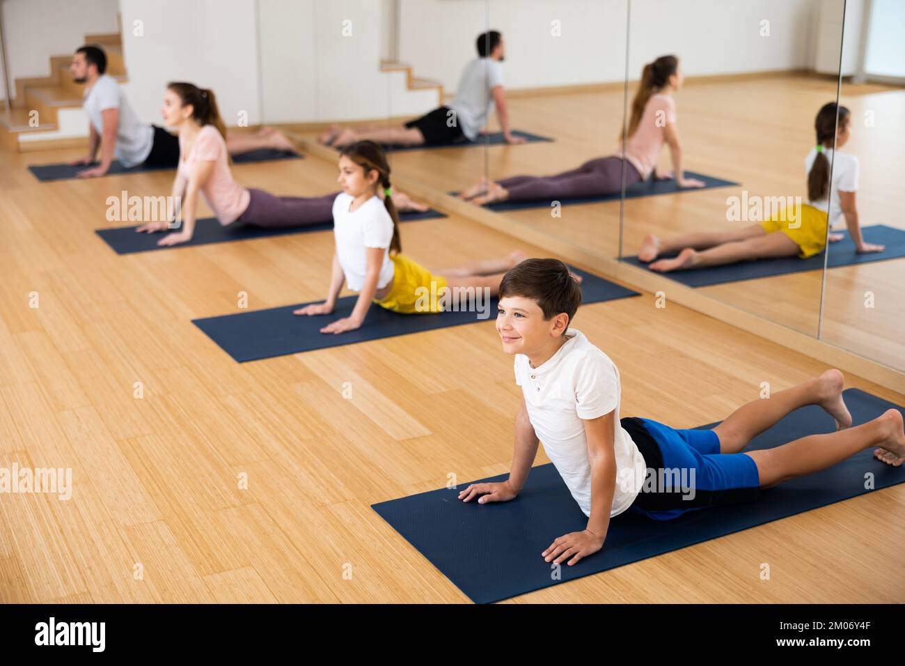 Boy doing stretching asana Bhujangasana during family yoga class Stock ...