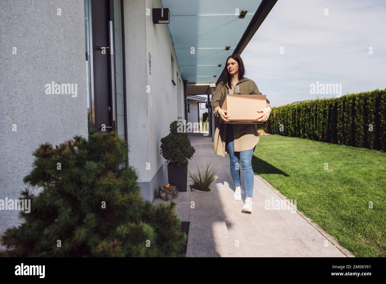Young caucasian woman carrying a box she got from the post office to ...