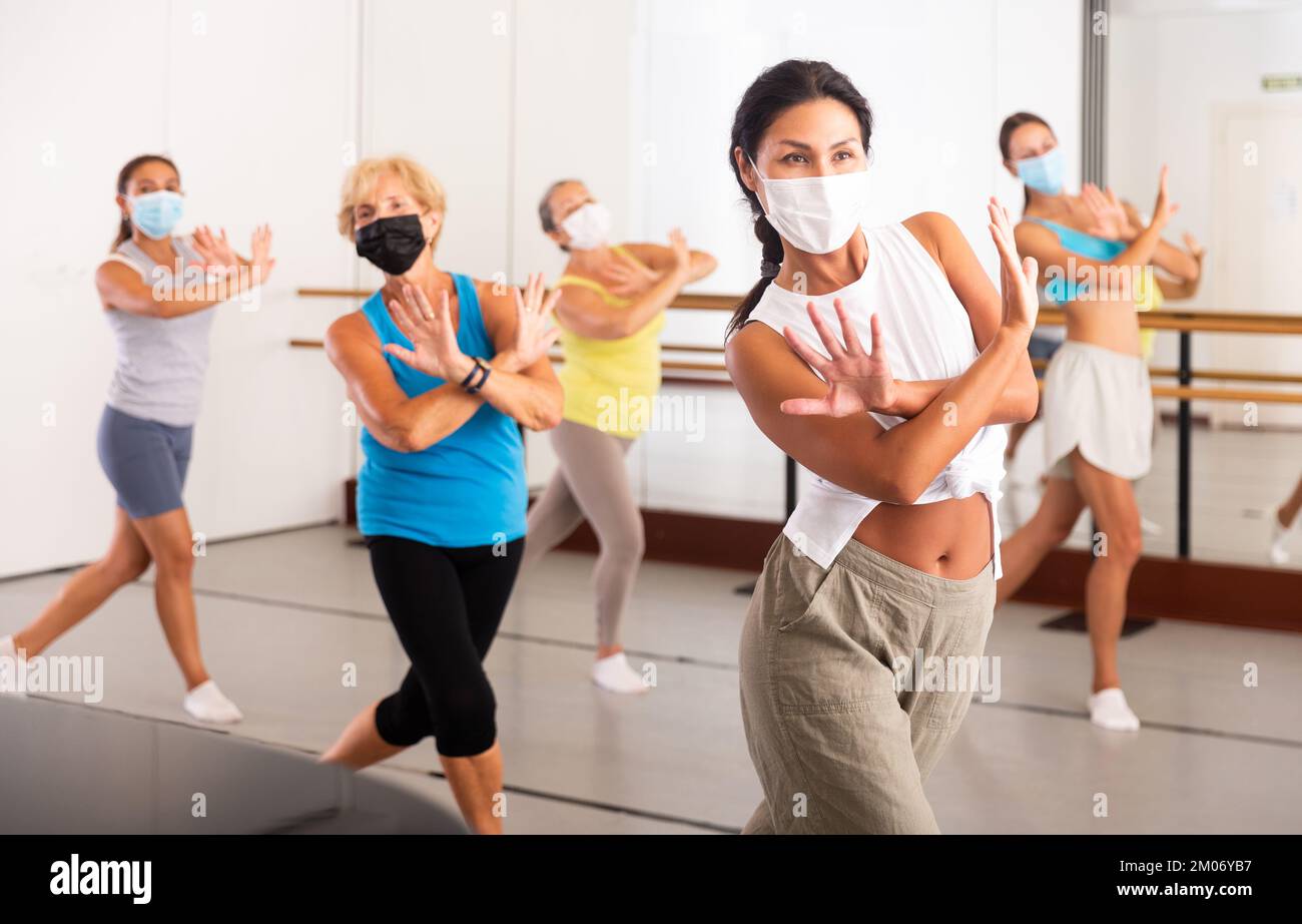 Dancing asian woman in a protective mask practices energetic swing in a ...