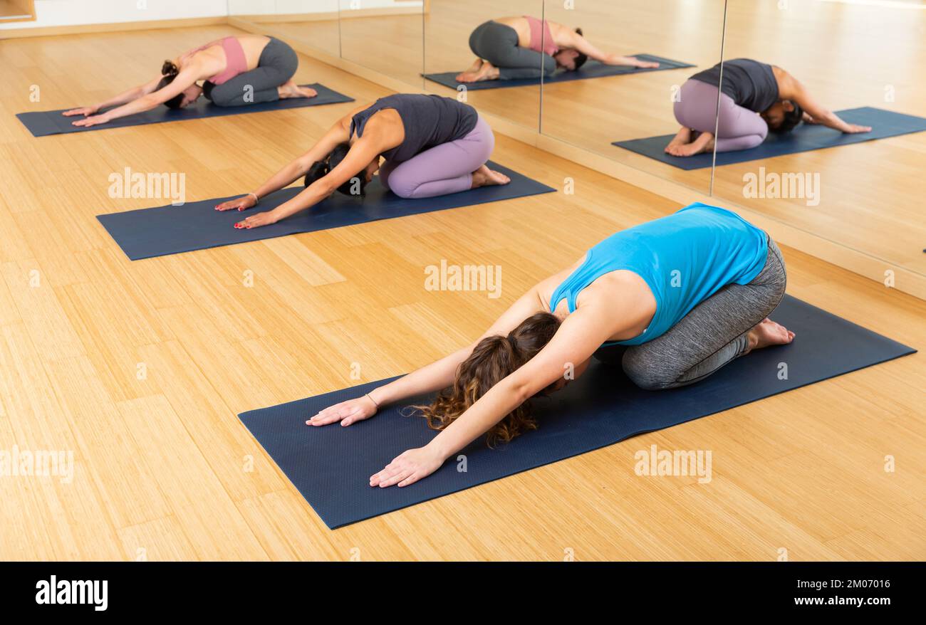 Group of women doing relaxing stretching workout in yoga studio Stock ...