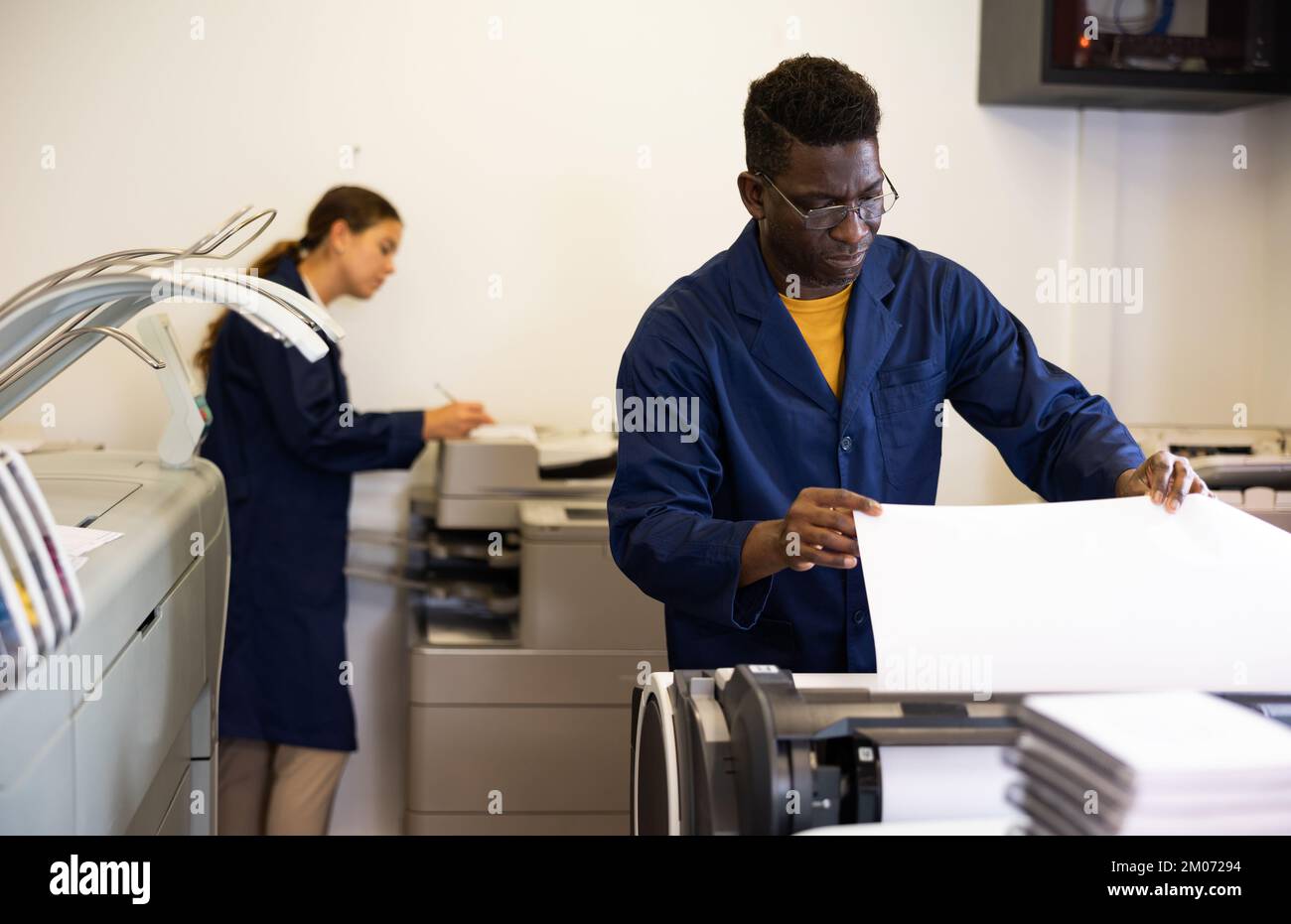 Focused African American male in a blue robe uniform using plotter ...