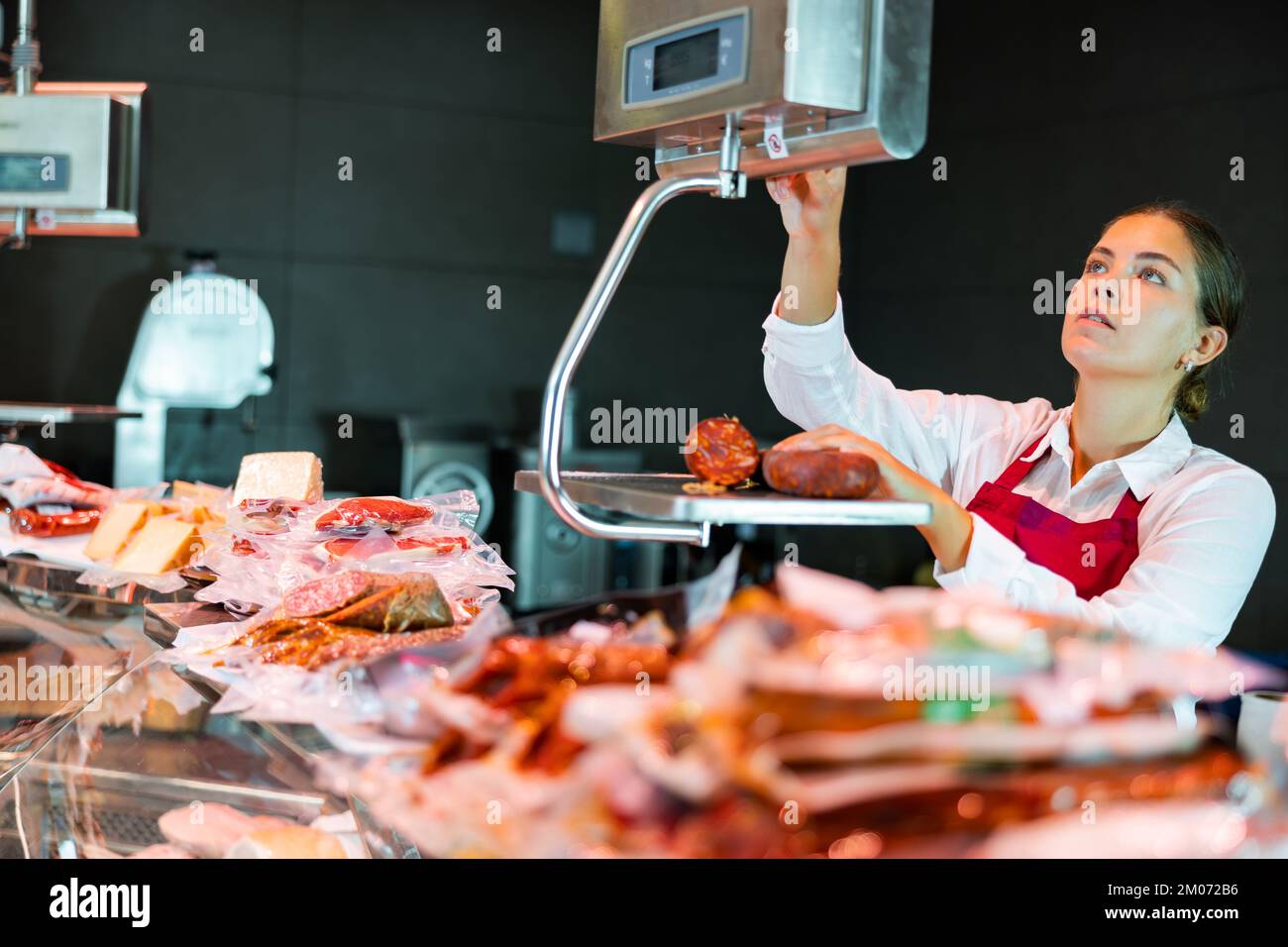 Female seller weighing sausage on scale in butcher shop Stock Photo - Alamy