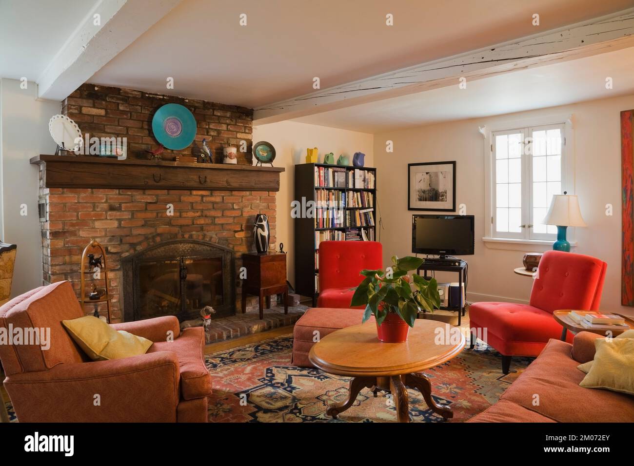 Salmon colored upholstered sofa, oval wood coffee table and red brick ...