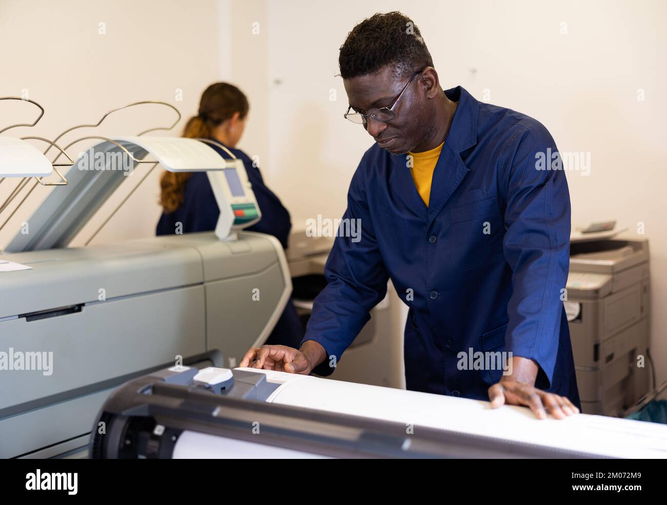 Attentive african american man uses plotter in printing shop Stock ...