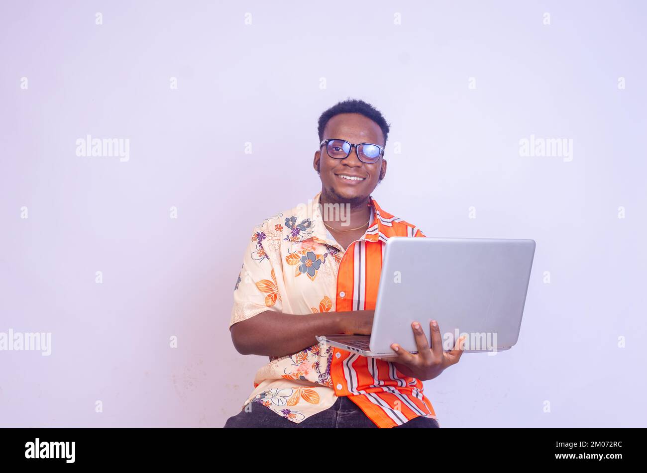 Young smiling african american man sitting and using laptop computer ...