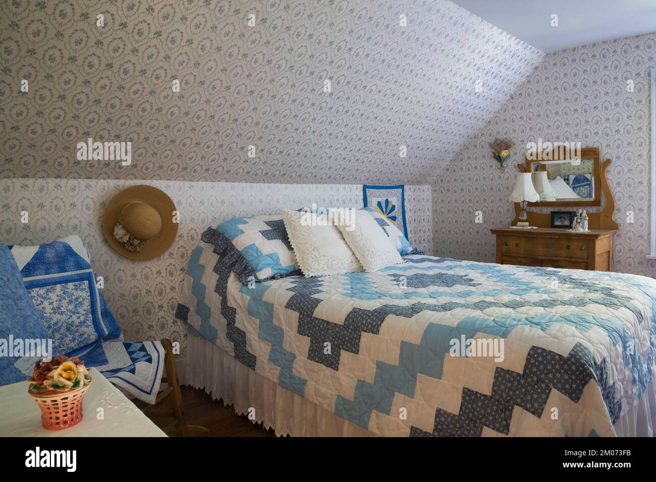 Double bed with blue nuanced patchwork bedspread and antique dresser in ...