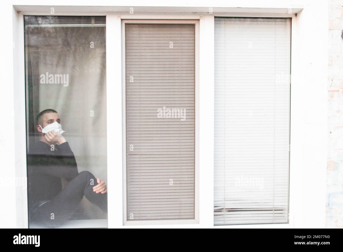 Upset young man sitting by the window and looking away. The concept of ...