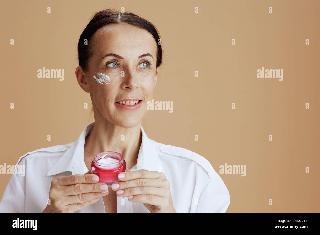 Happy Modern Middle Aged Woman With Facial Cream Jar In White Shirt