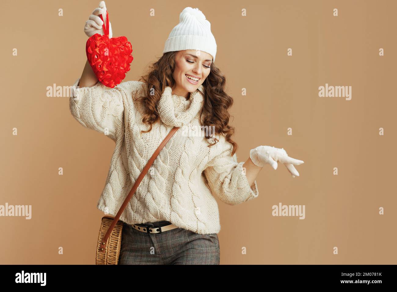 Hello winter. smiling trendy woman in beige sweater, mittens and hat ...