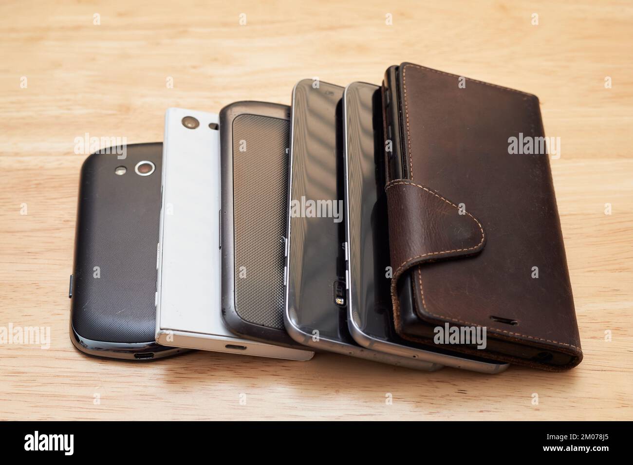 a bunch of old used up cell phones from different decades piled up on ...