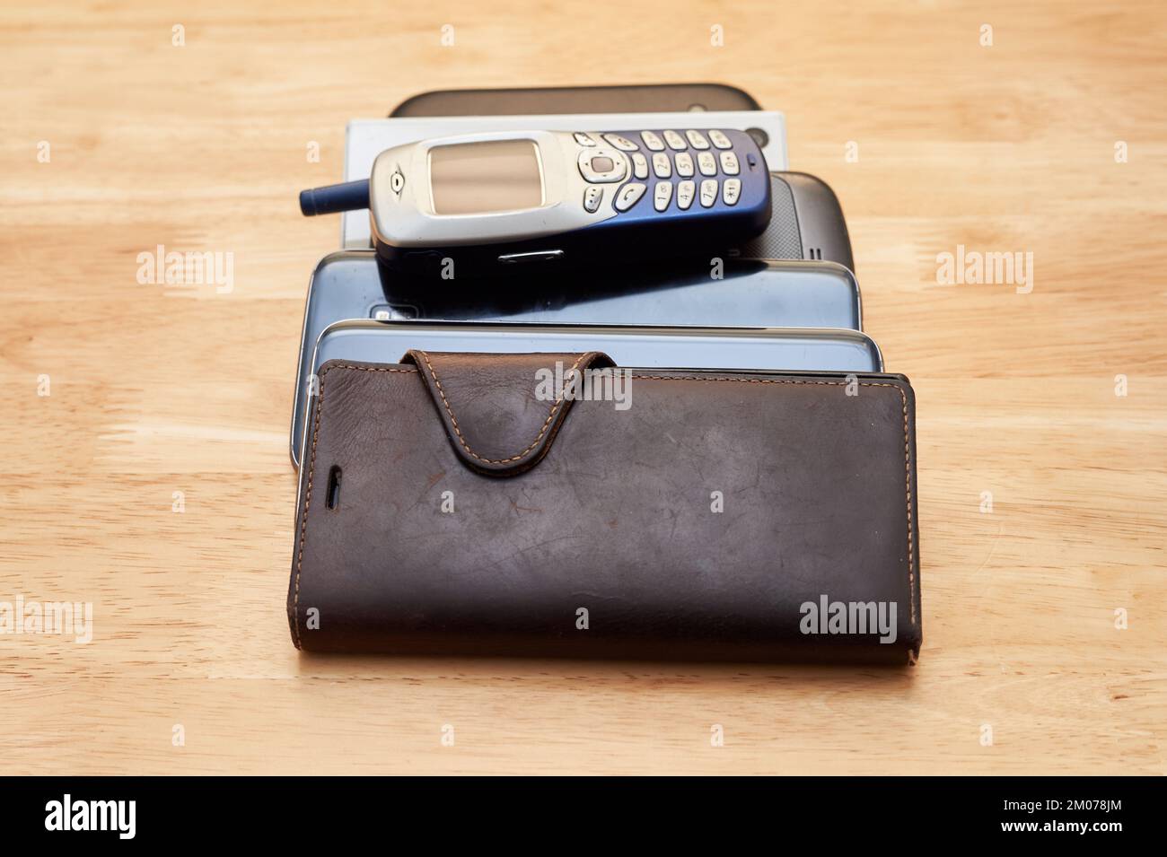a bunch of old used up cell phones from different decades piled up on ...
