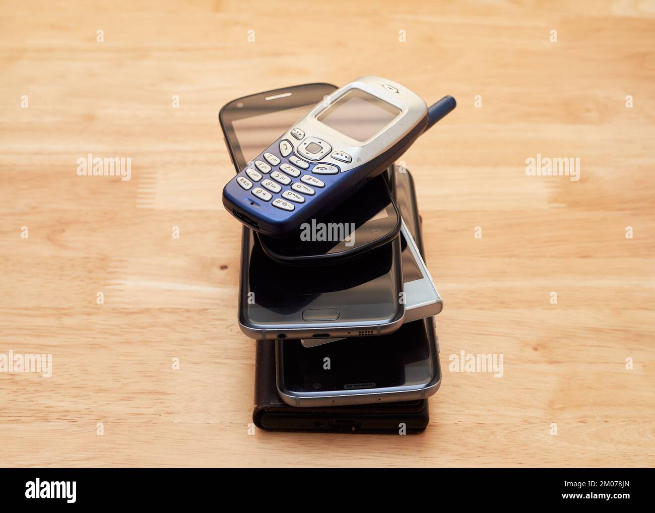 a bunch of old used up cell phones from different decades piled up on ...