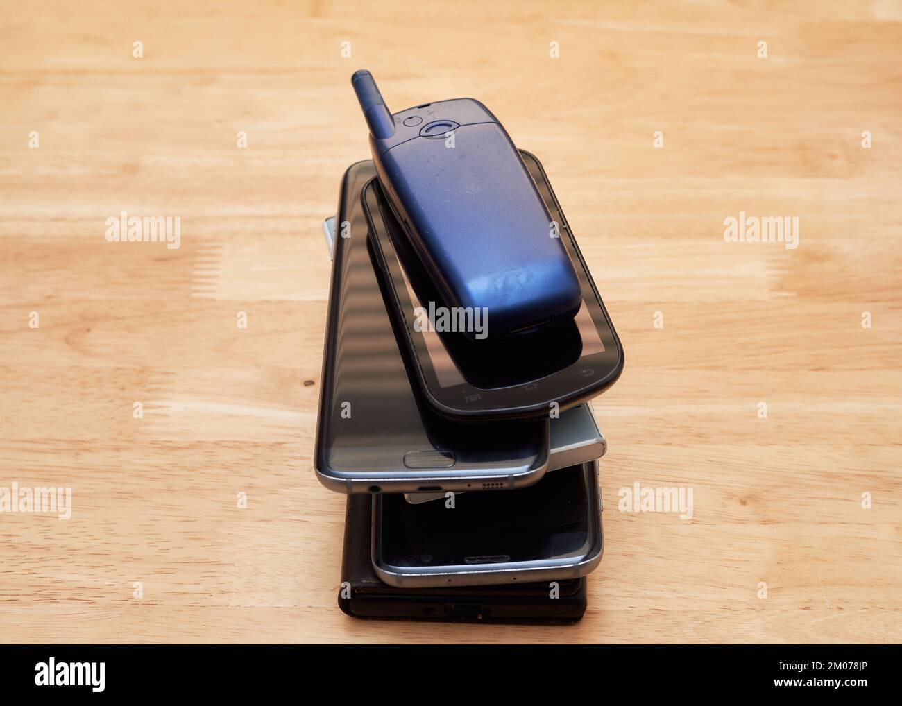 a bunch of old used up cell phones from different decades piled up on ...