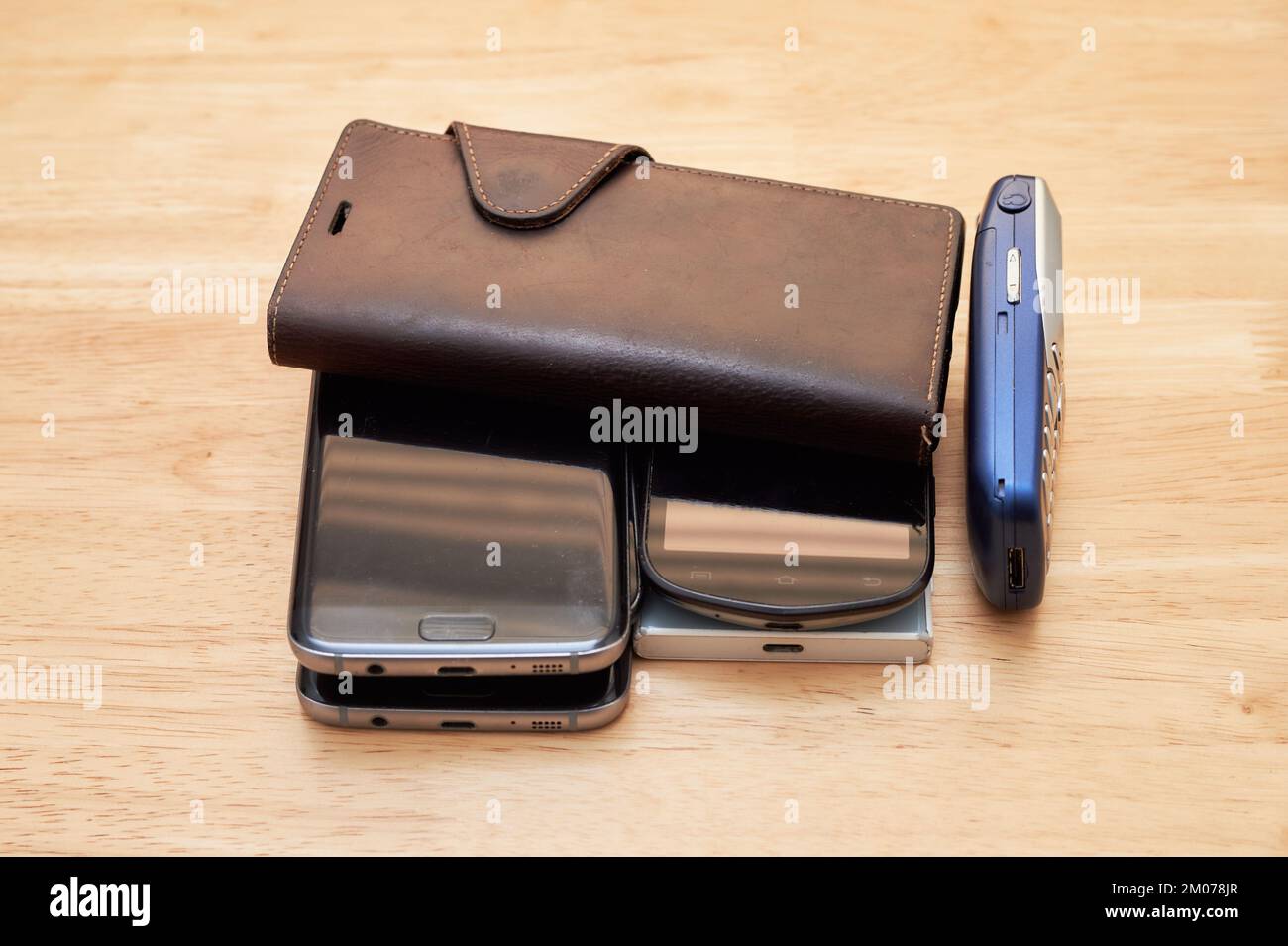 a bunch of old used up cell phones from different decades piled up on ...