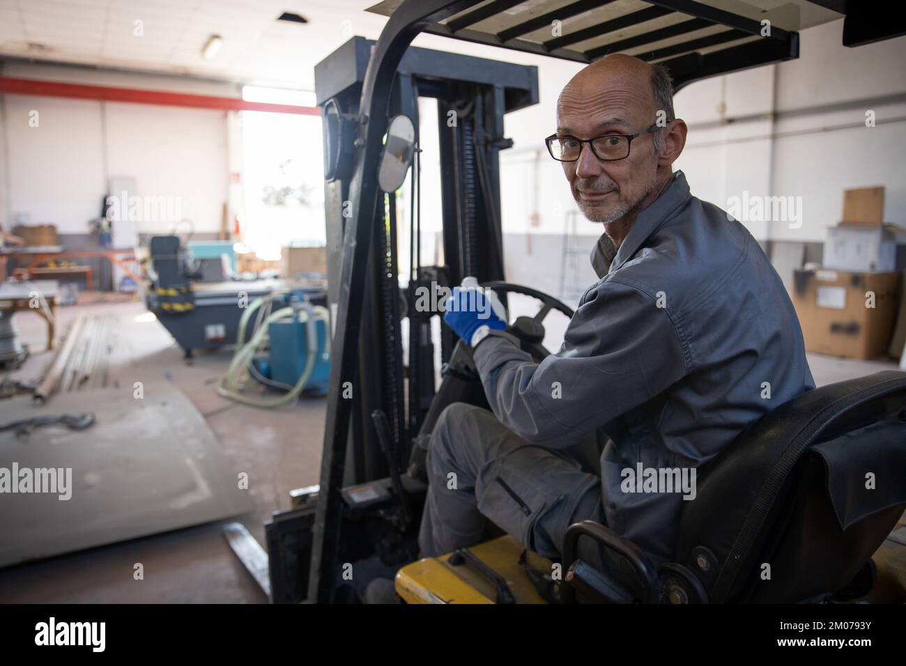 A worker drives the mechanical forklift during work in the warehouse ...