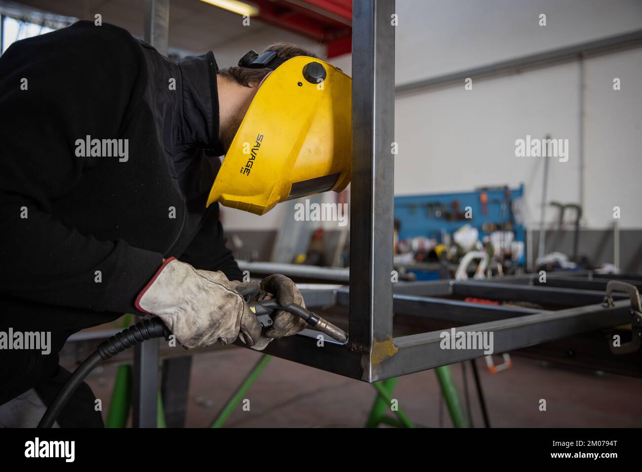 A worker uses a welding machine to weld two metal bars in a workshop ...