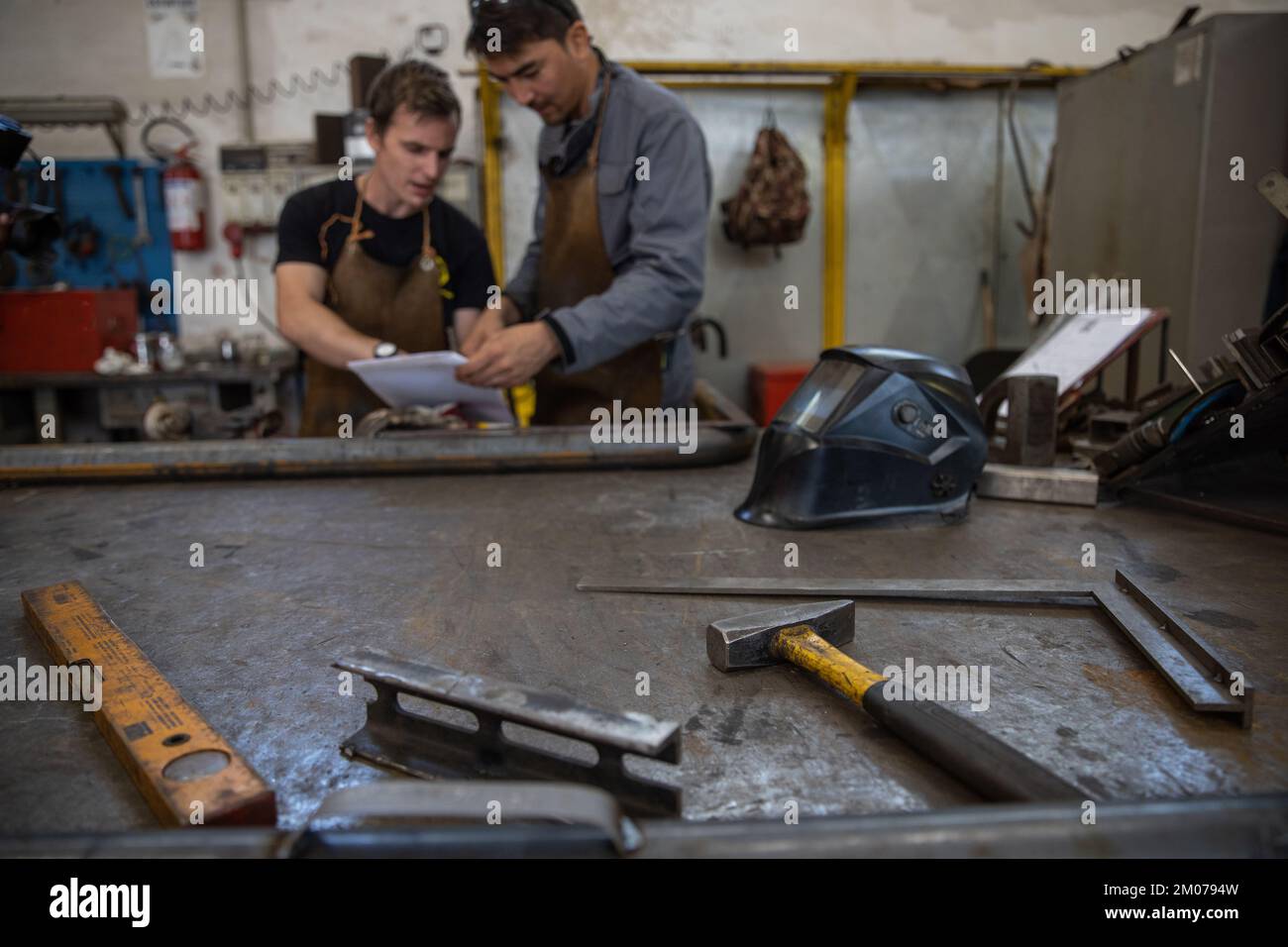 Two fellow workers look at the technical drawings in the factory, focus ...