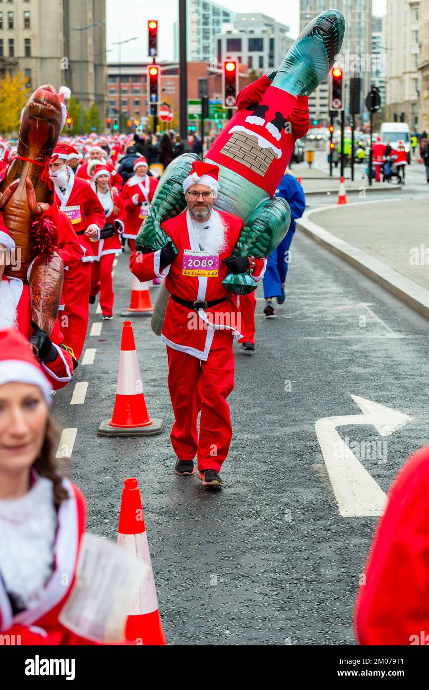 A man in a costume carries an inflatable dinosaur during the annual ...