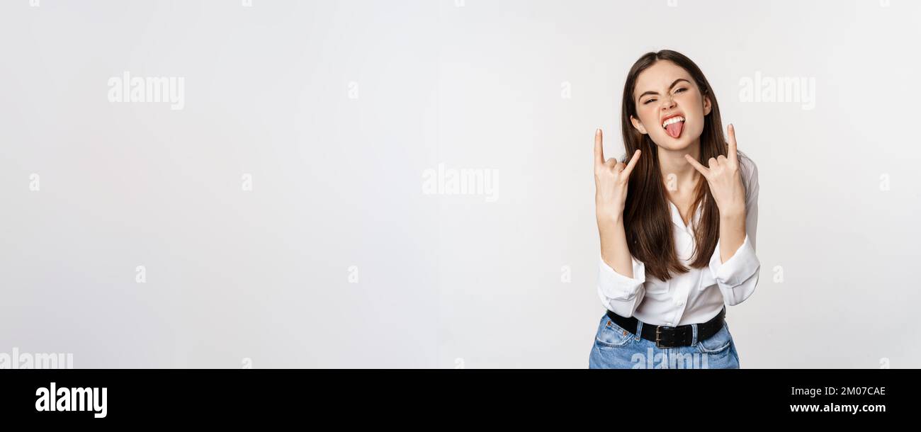 Rock n roll. Young woman showing rock on, heavy metal sign, having fun ...