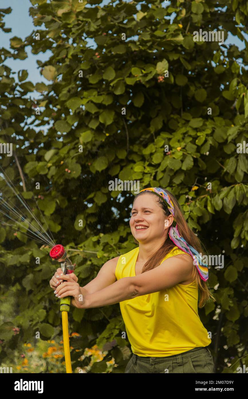 Summer garden, watering - beautiful girl watering roses with garden ...