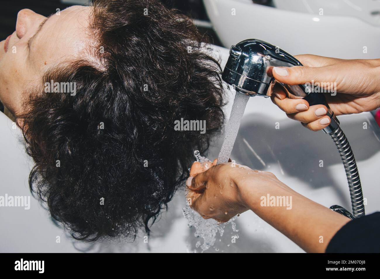 Gorgeous cheerful elderly woman enjoys a head massage while washing her ...