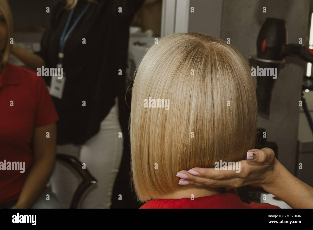 Closeup of a hairdresser cuts wet white hair of a client in a salon ...