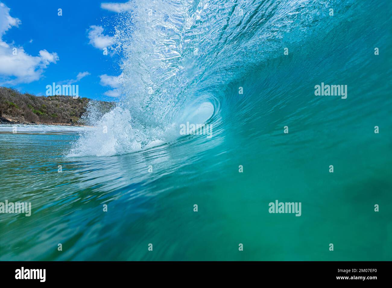 Tubular wave breaking into the crystalline emerald green sea and ...