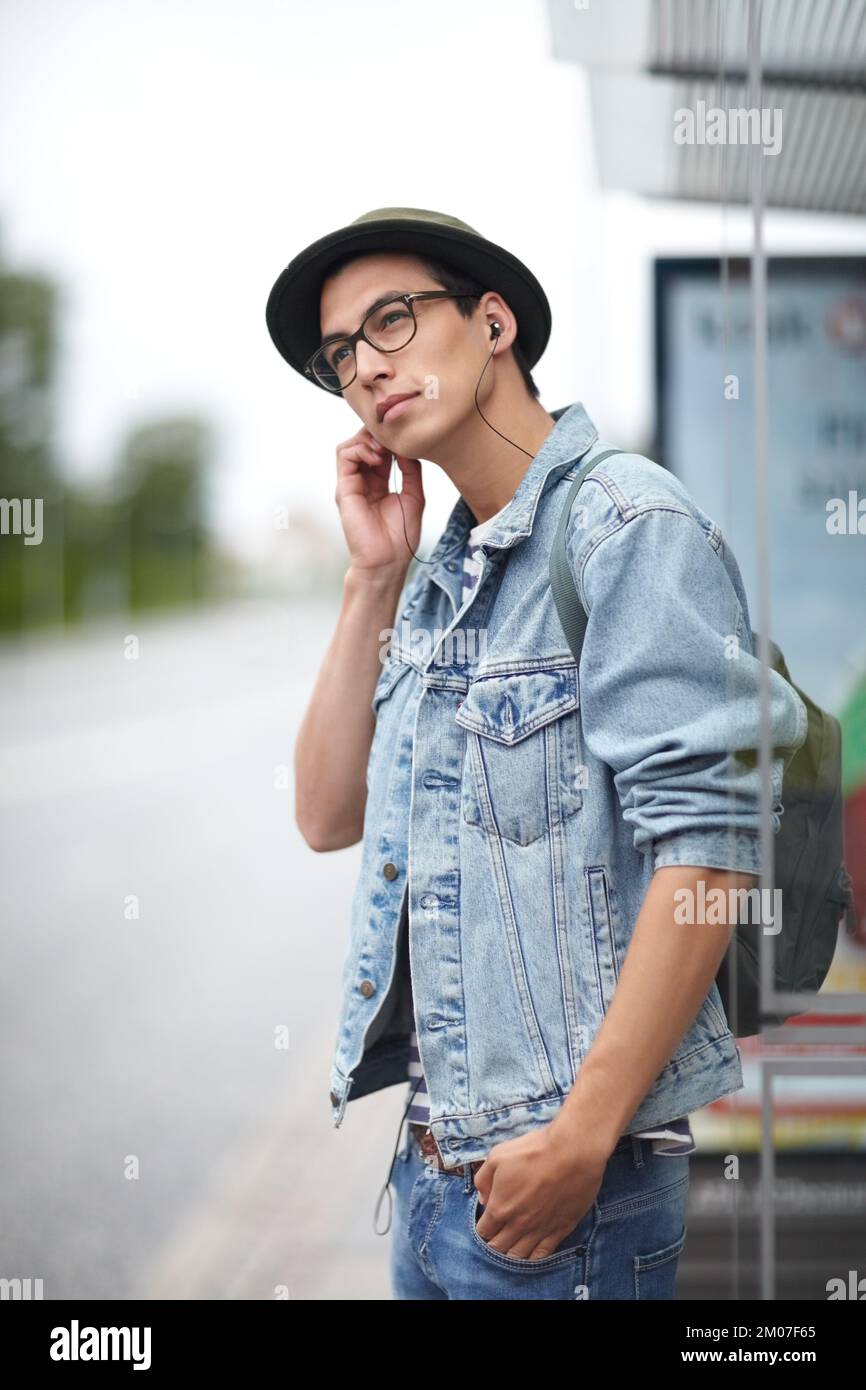 Waiting for the bus. Hip young guy standing at a bus stop with his ...