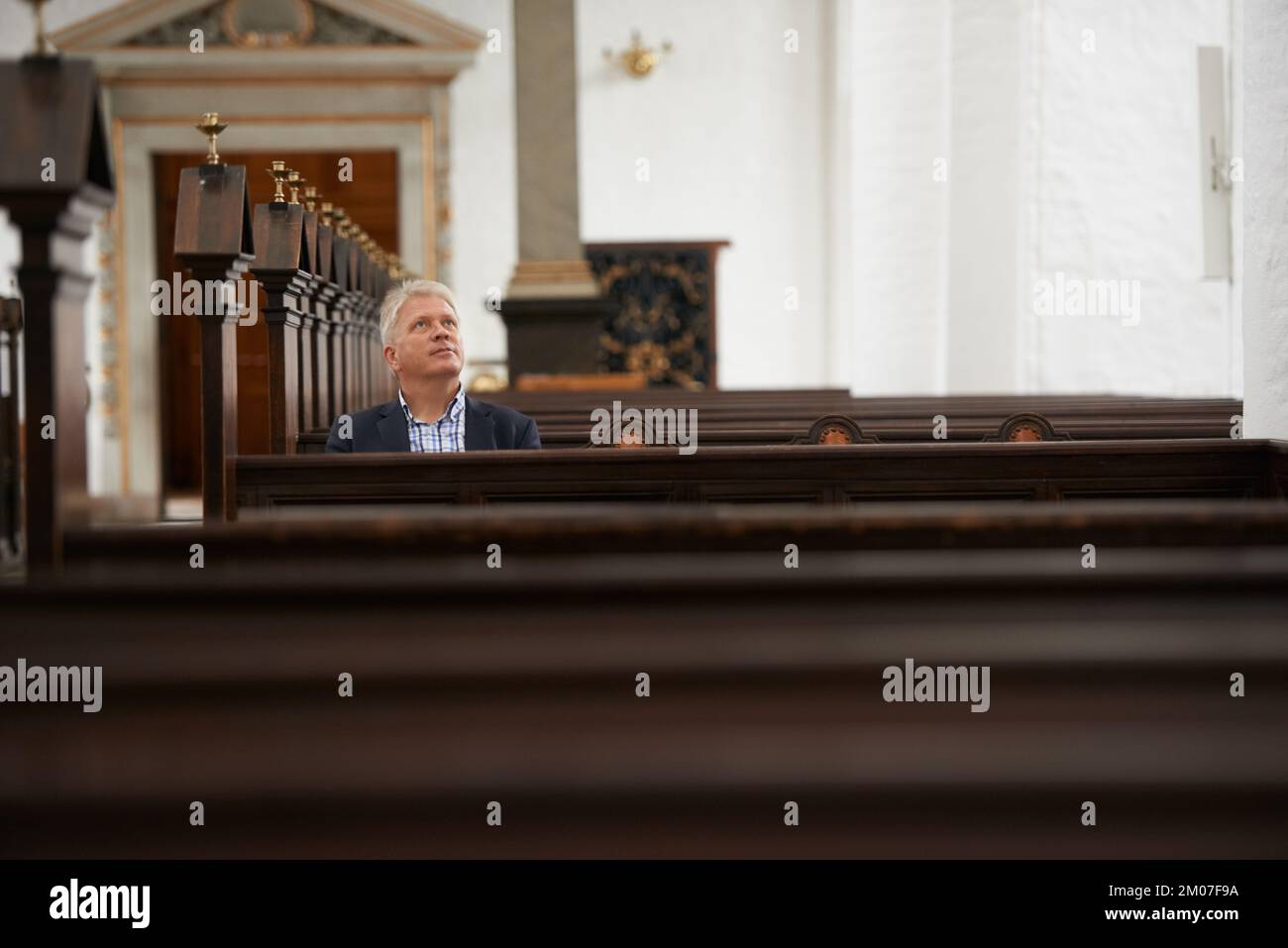 Hes a very religious man. A senior man sitting down in his local church ...