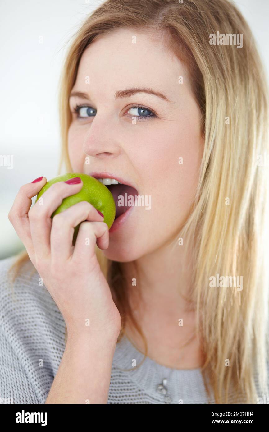Having a quick snack. Cute young woman biting into a fresh apple - portrait Stock Photo - Alamy