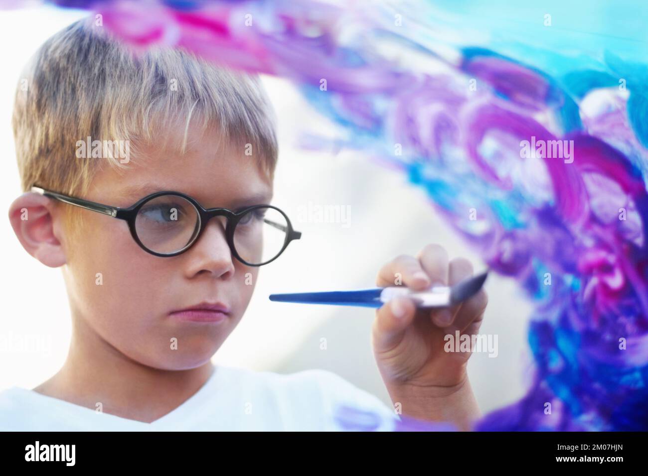 Creativity and talent. Focused little boy painting on glass and ...