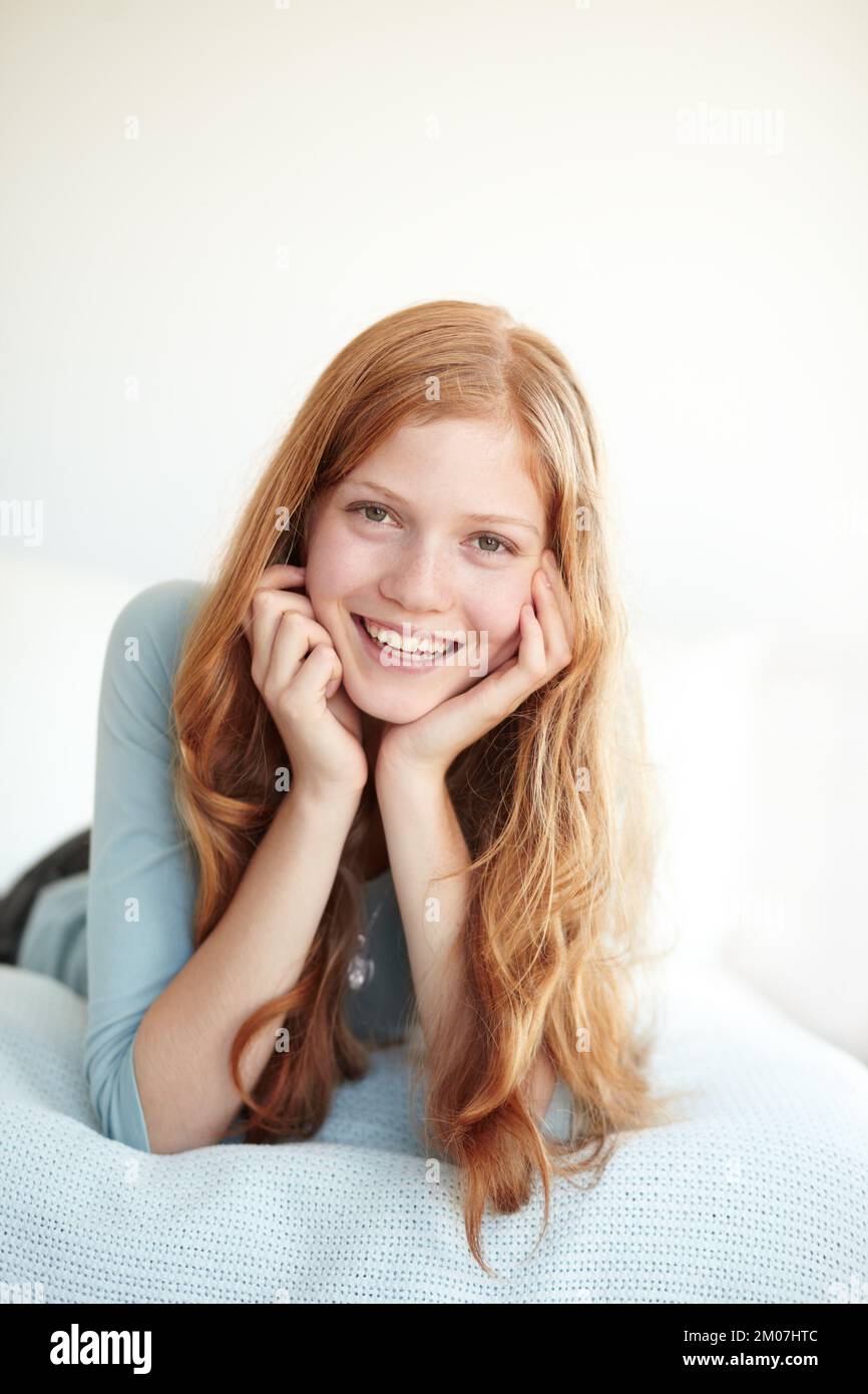 Relaxed and casual at home. Portrait of a young girl lying on her bed ...