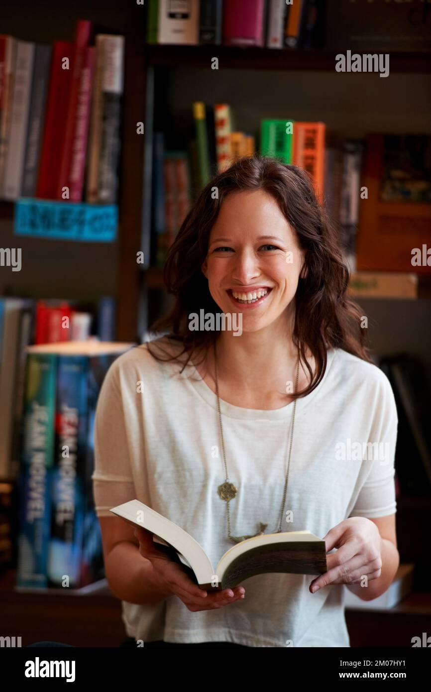 Who needs the internet. Portrait of a smiling young woman reading a ...