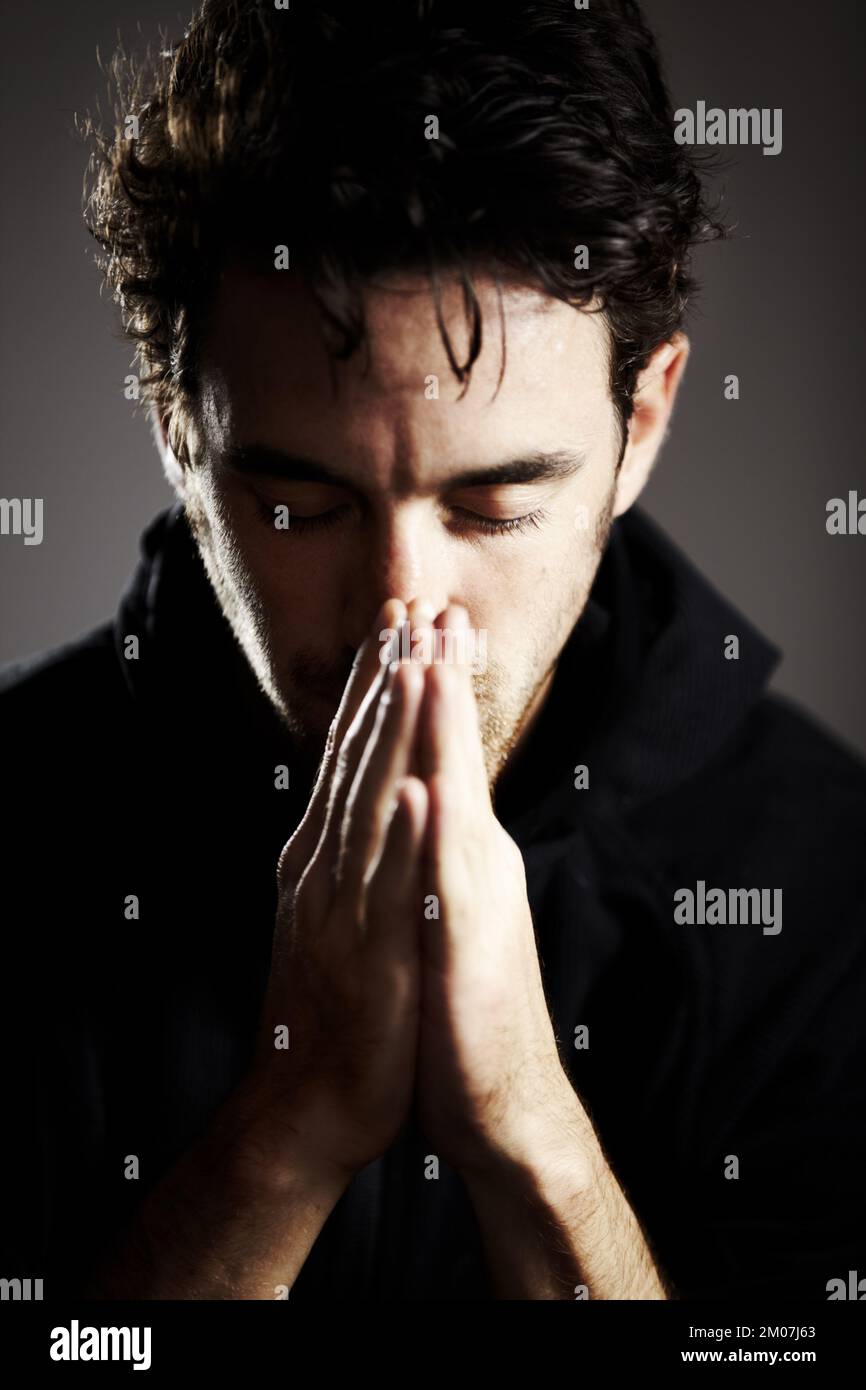 Hes deep in prayer. A young man with his hands together and eyes closed ...