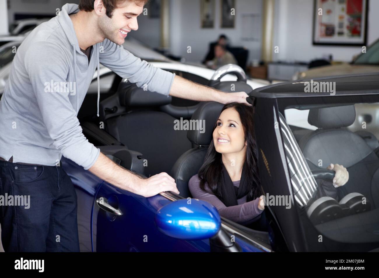Do you like it. Beautiful young woman at a car dealership trying out ...