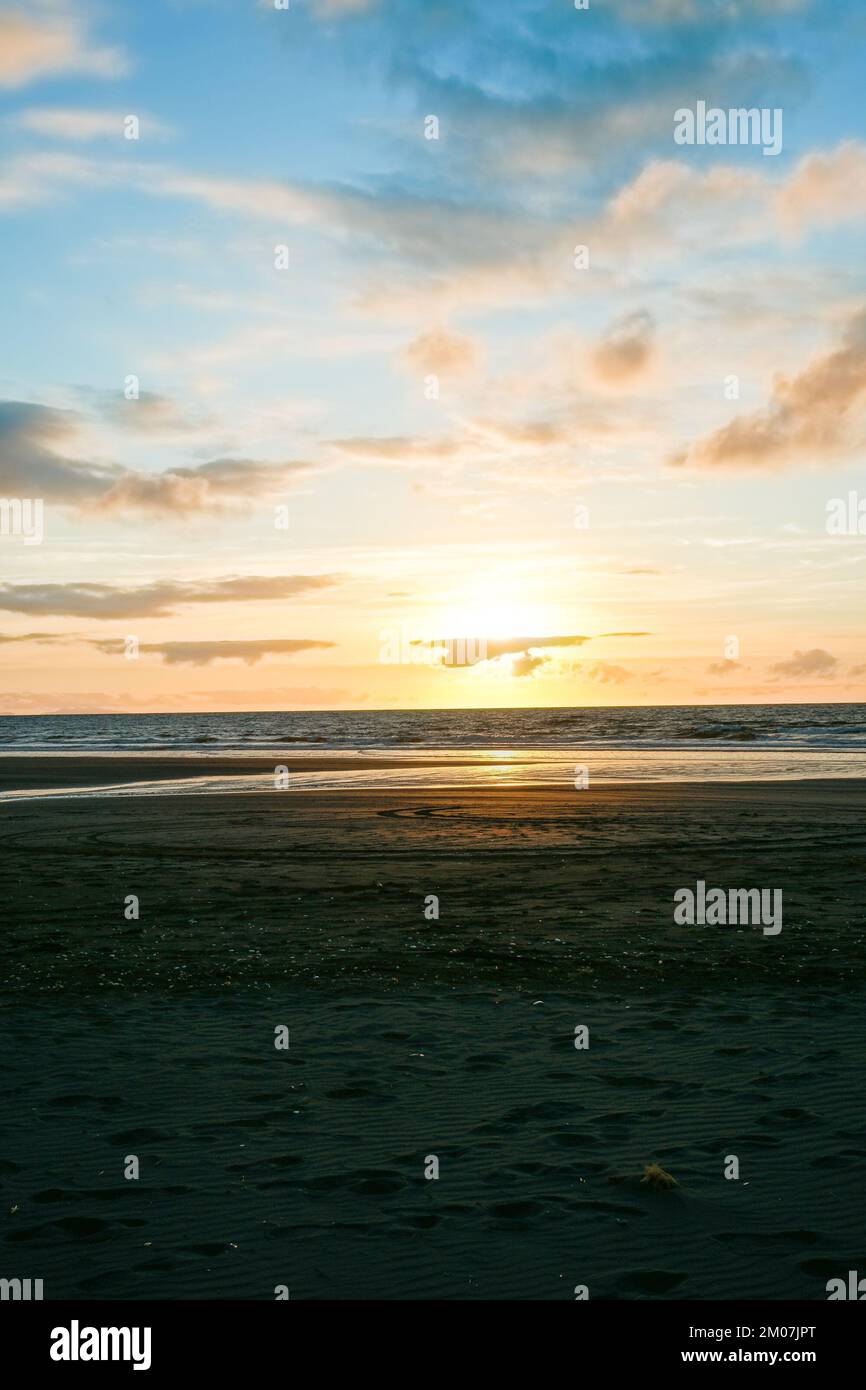 Beach in silhouette as sunsets on distant horizon over ocean Stock ...