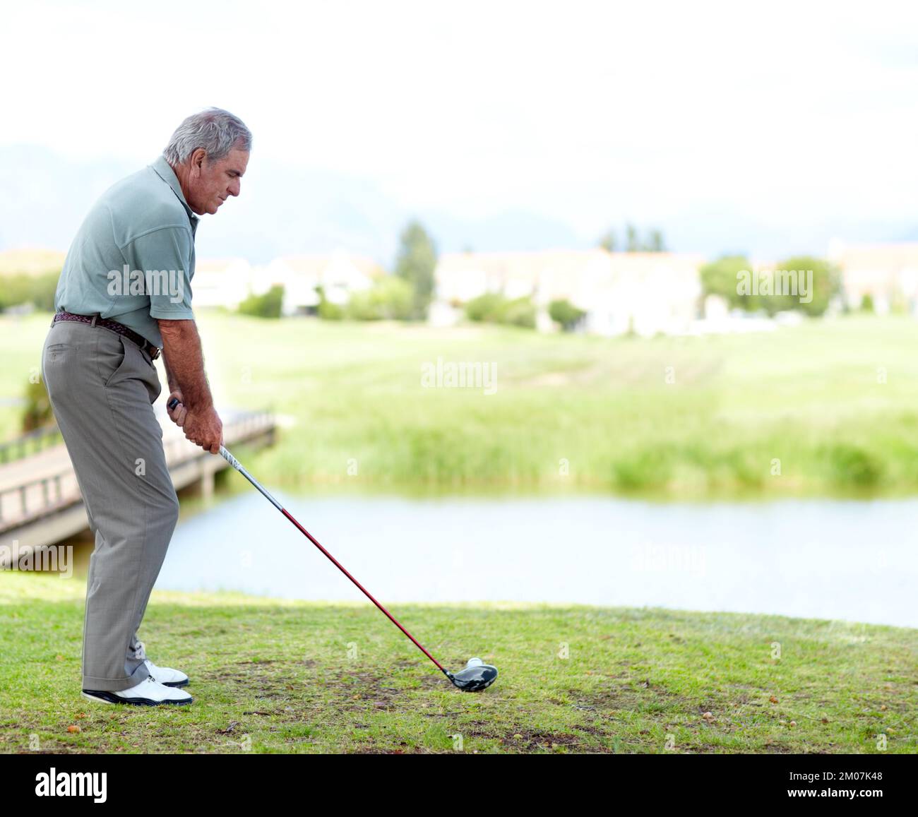 Golf is a game of the mind. A senior man concentrating while teeing up ...