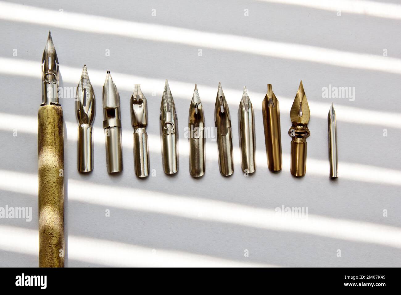 metal tips for the ink pen on a white background in solar rays ...