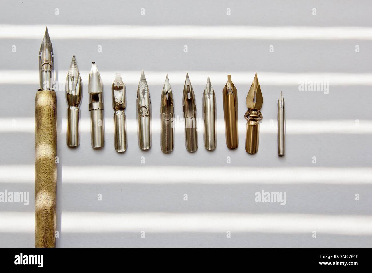 metal tips for the ink pen on a white background in solar rays ...