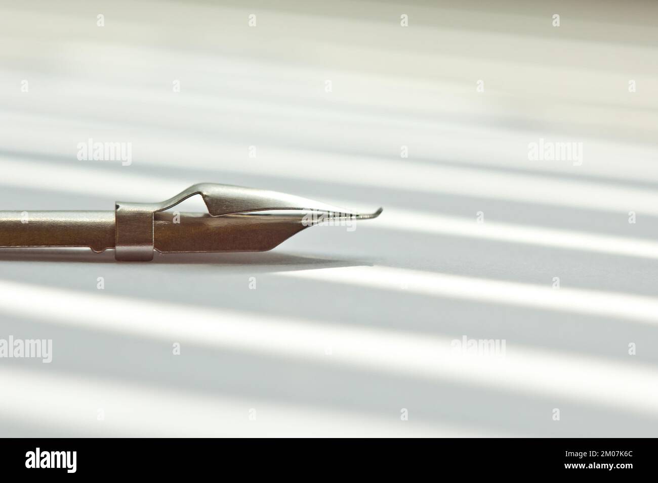 metal tip for the ink pen on a white background in solar rays ...