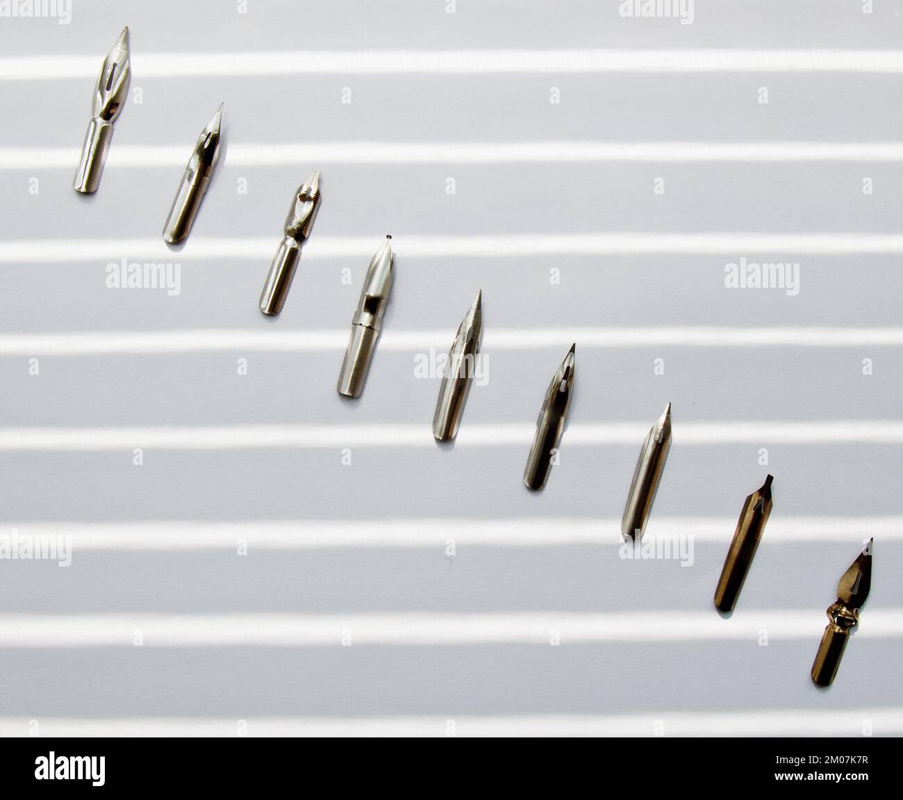 metal tips for the ink pen on a white background in solar rays ...