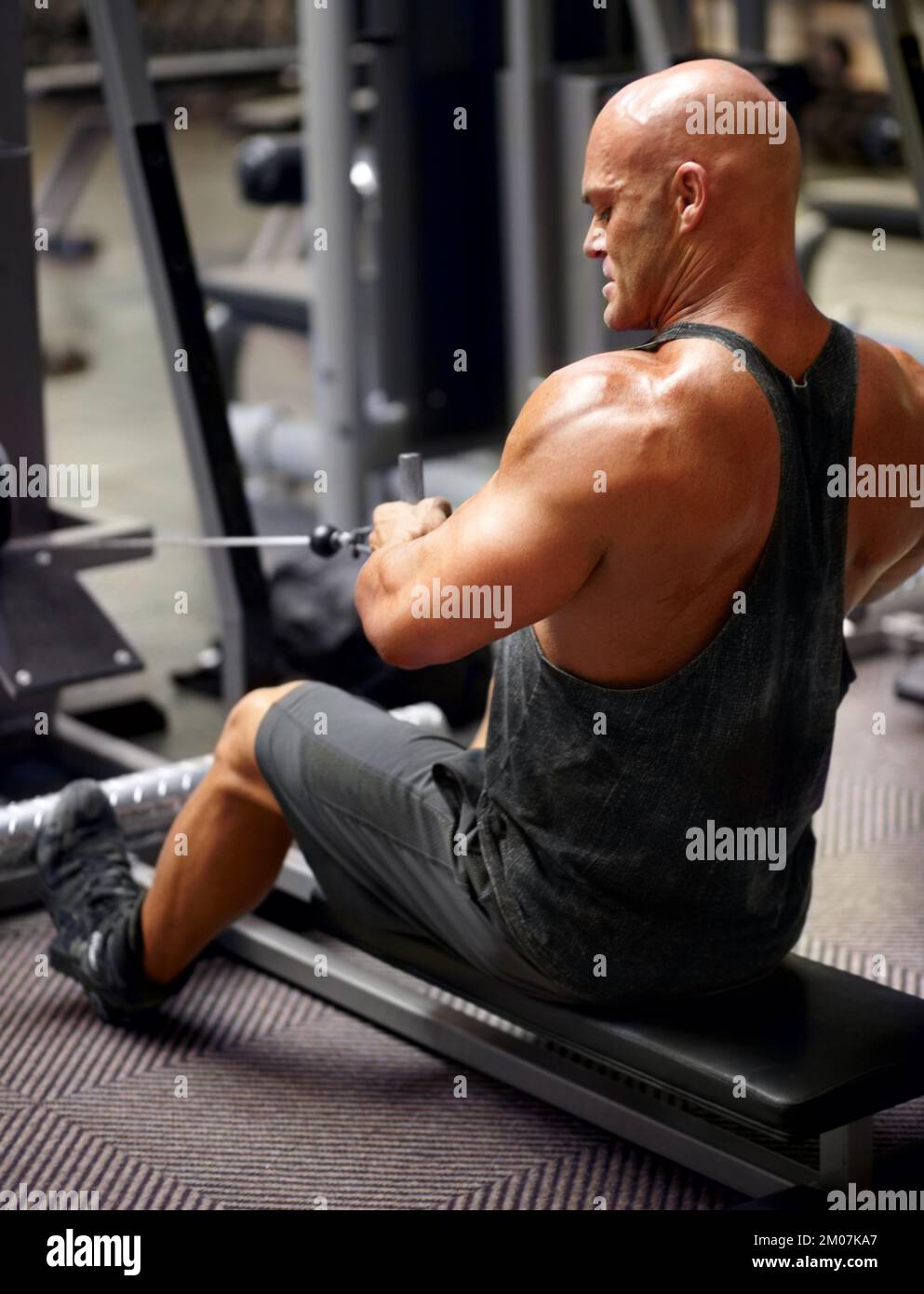 Building up his bulging muscles. Rearview shot of a male bodybuilder ...