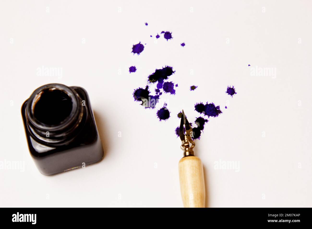 ink stain drawn with an ink pen on a white paper sheet with inkwell ...