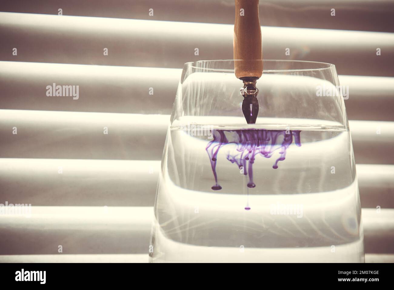 metal tip of ink pen dipped in water. diffusion of blue ink in a ...