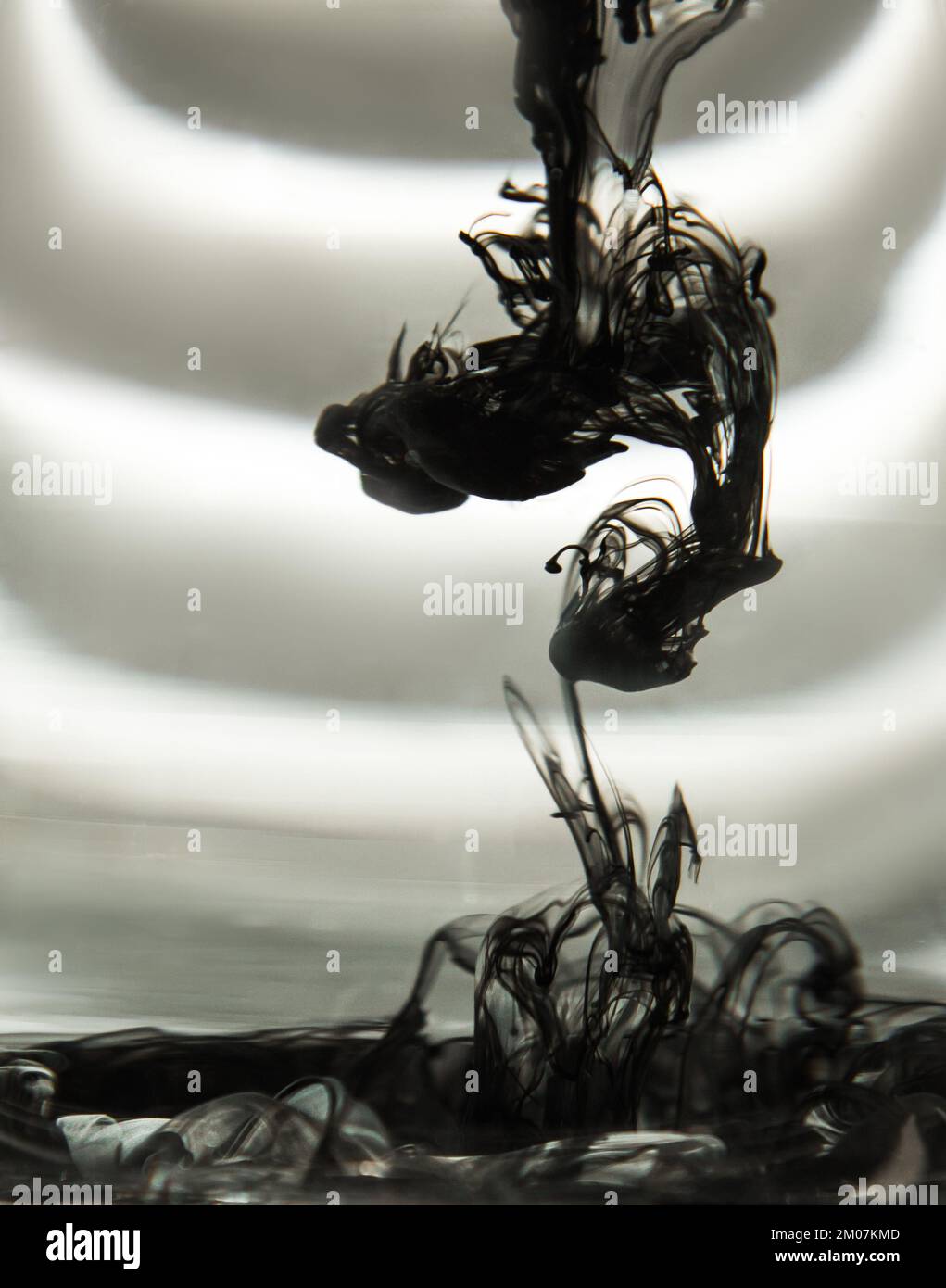 a cloud of ink in a transparent glass cup with clear water against the ...