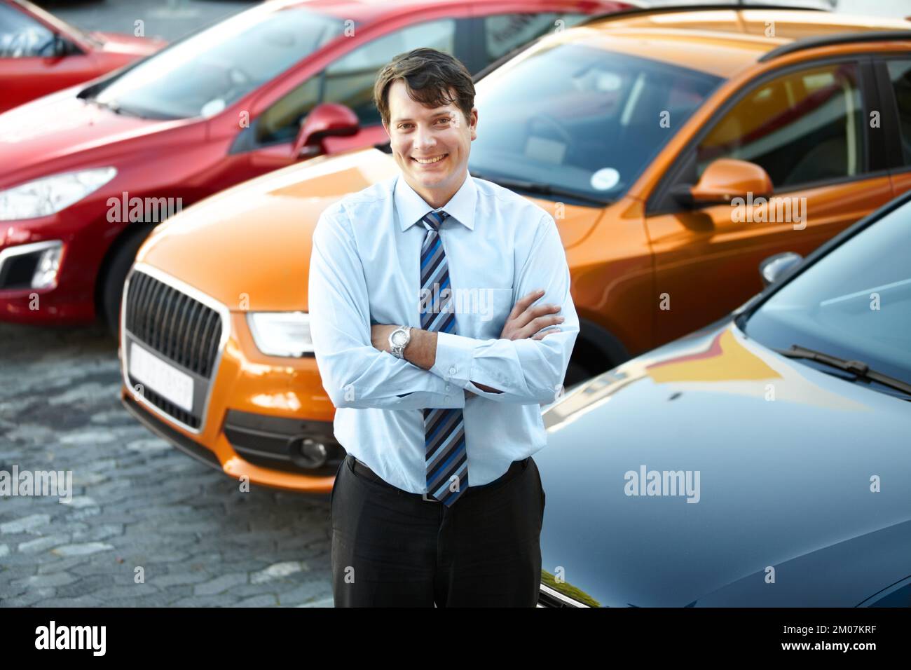 The best car dealer in town. A man smiling proudly while standing in ...
