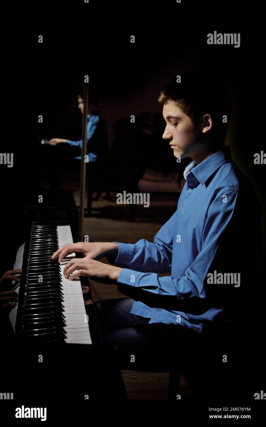 young man sitting at the piano. boy emotionally plays the keyboard ...