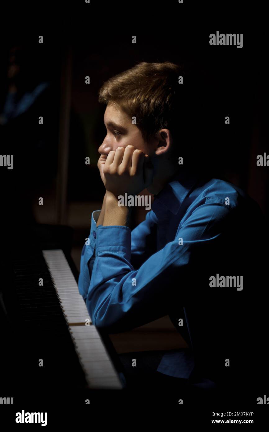 young man sitting at the piano. the boy wondered how he played the ...